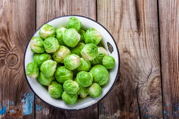 Frisse biologyske spruiten yn in kom op in houten tafel