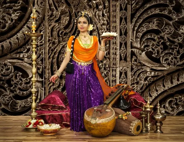 Girl in Indian national costume with a dish of sweets in her hand