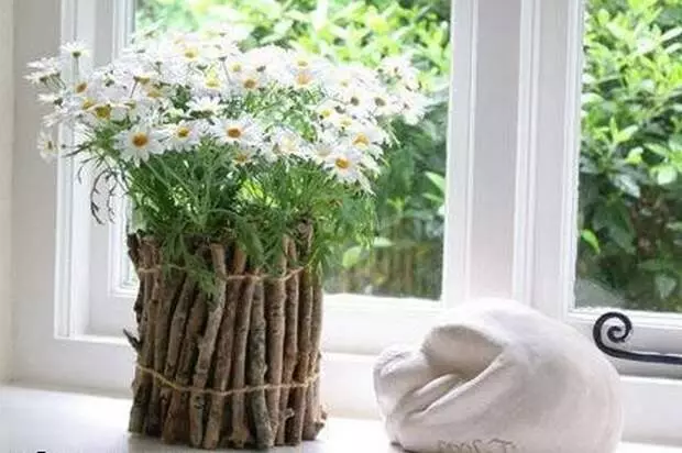 Cvetlični lonec, okrašen z lesenimi palicami